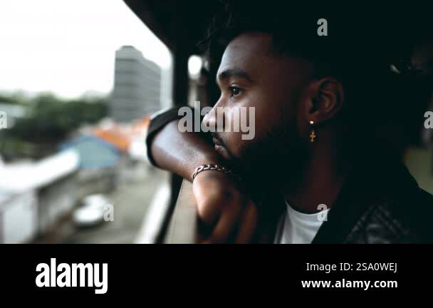 One pensive young black man standing at balcony leaning on metal bar ... One pensive young black man standing at balcony leaning on metal bar ...