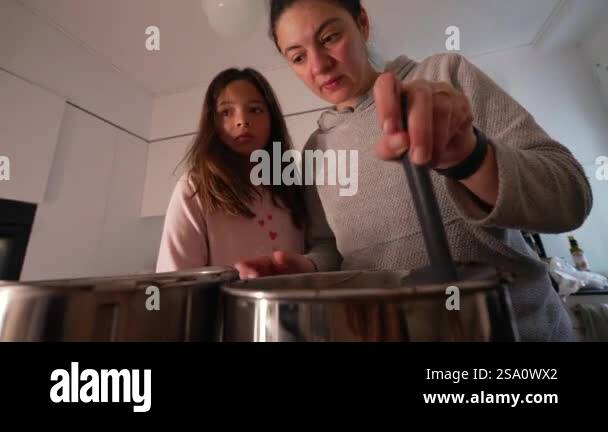 Mother tasting chocolate while preparing cake standing in kitchen with ...
