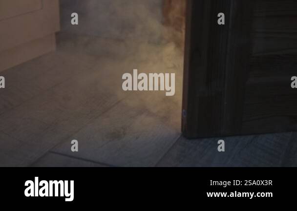 Smoke seeping through a doorway from a house fire, indicating danger ...