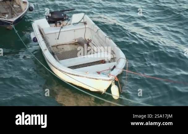 Small weathered boat is anchored in serene waters, bobbing gently. Calm ...