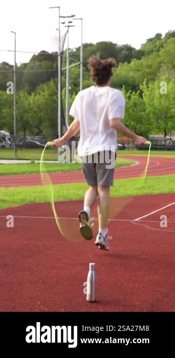 Vertical full length video of a caucasian young man warming up skipping ...