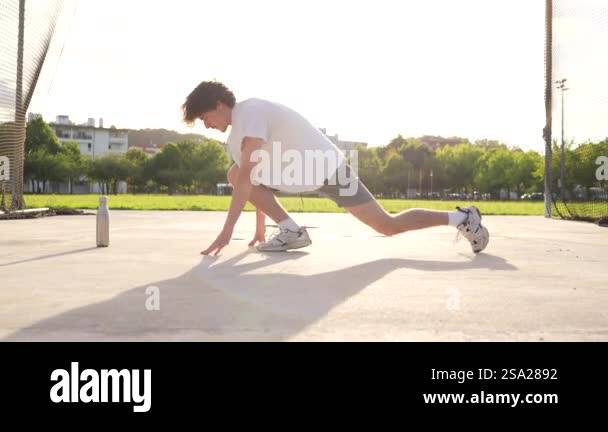 A caucasian young serious skinny man stretching before training in a ...
