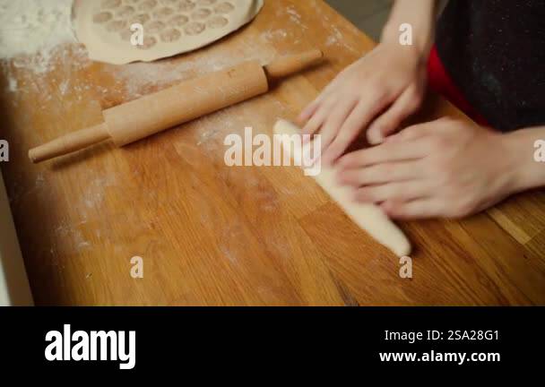 Teenager rolling dough with hands forming smooth cylindrical shape ...