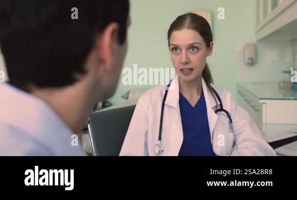Confident young medical professional woman talking to male patient with ...