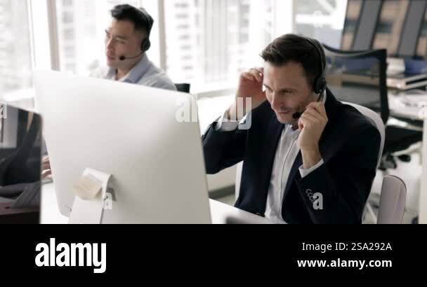 Positive friendly salesman in wireless headset talking to client on ...