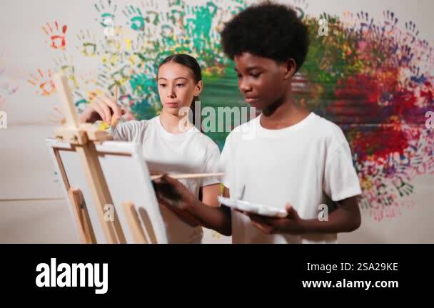 Diverse happy children paint canvas together with colorful stained wall ...