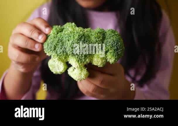A child examines a unique piece of broccoli that resembles a car. The ...