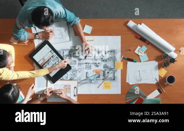 Top down aerial view of smart engineer looking at blueprint at meeting room. Skilled architect ...