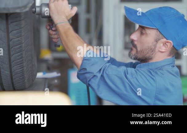 Professional male mechanic doing a wheel replacement in the auto repair ...