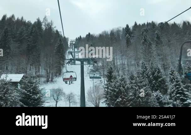 Aerial view over snowy mountain winter forest with chair lift at ski ...