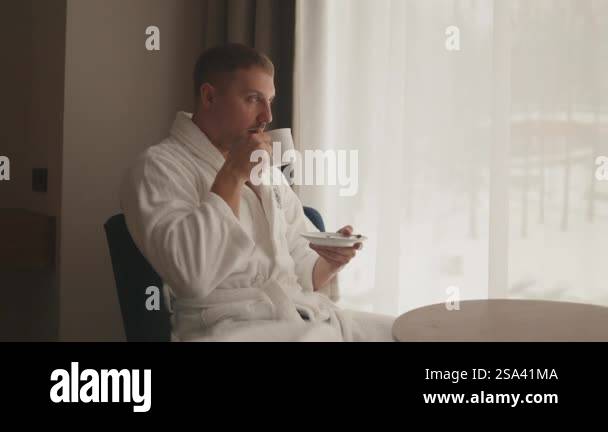 Profile of a happy man in a white coat smelling coffee siting on a ...