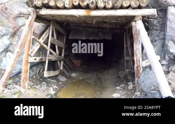 An abandoned old mine in Rocky Mountain. A puddle at the entrance and a ...