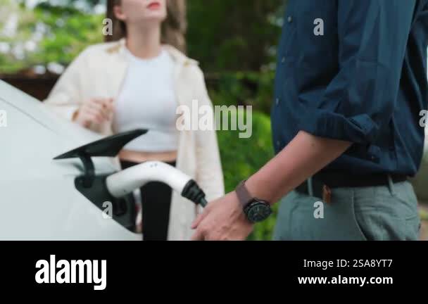 Young couple recharge electric cars battery from charging station in ...