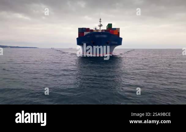 Front view of a blue container ship sailing through calm waters under a ...