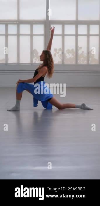 A medium shot of a woman gracefully stretching and preparing her body for a contemporary dance ...