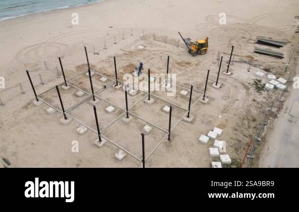 Construction site on a sandy beach near the sea, featuring structural ...