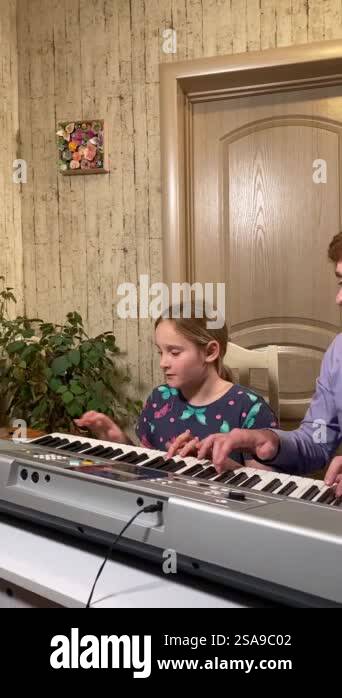 A young music teacher guides a child in learning to play the musical ...