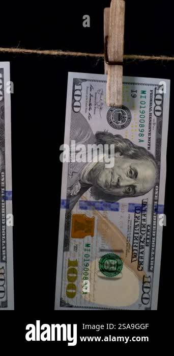 Dollars dry on a clothespin rope on a black background. The financial ...
