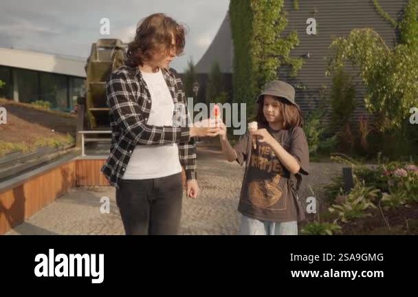 Two brothers are walking together in a city park on a sunny summer day ...