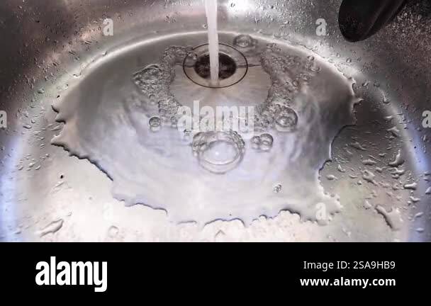 Slow motion recording of running water in a lightly soiled metal ...