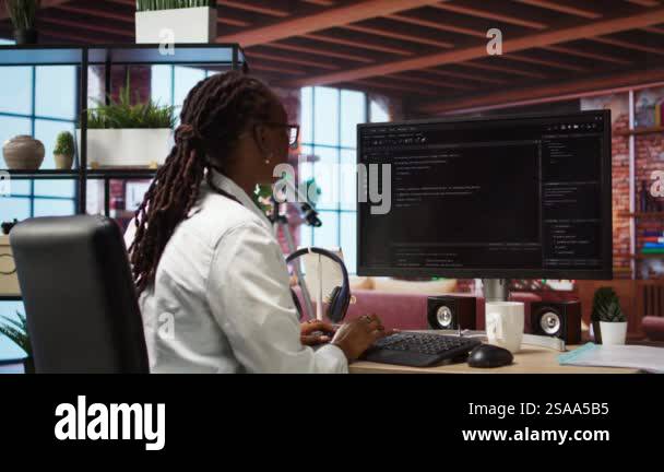 Developer at computer desk coding while listening music, creating software, implementing ...