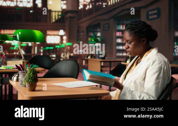 Black medical student reading healthcare books at the campus library ...