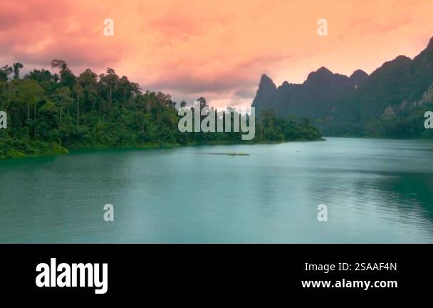 Cheow Lan Lake at sunrise showcases stunning rock formations surrounded ...