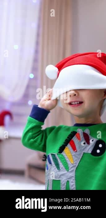 Little cute kid hiding under the red Santa cap. Smiling baby playing ...