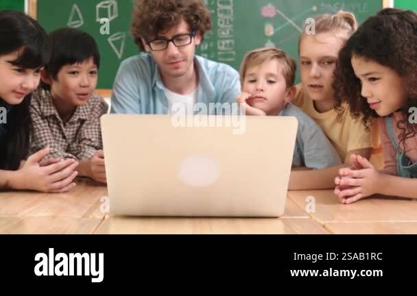 Caucasian teacher and diverse student looking at laptop at classroom ...