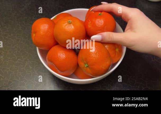 bright oranges tangerines stand in a white plate on a black table a ...