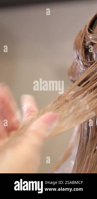 A qualified professional performs a hair coloring procedure in a chic ...