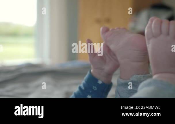Little baby is joyfully engaging with their tiny feet while lying ...