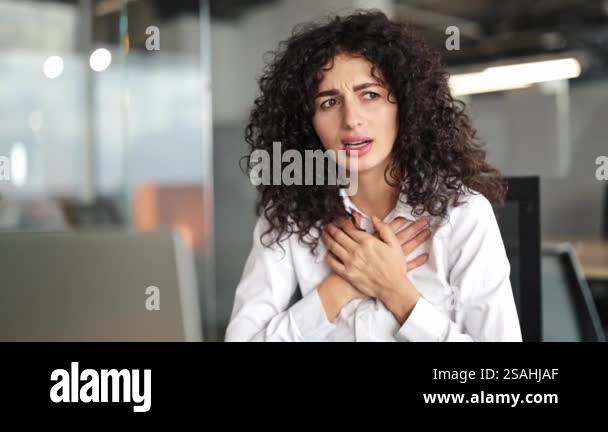 Curly-haired businesswoman in office suffering from sudden chest pain ...