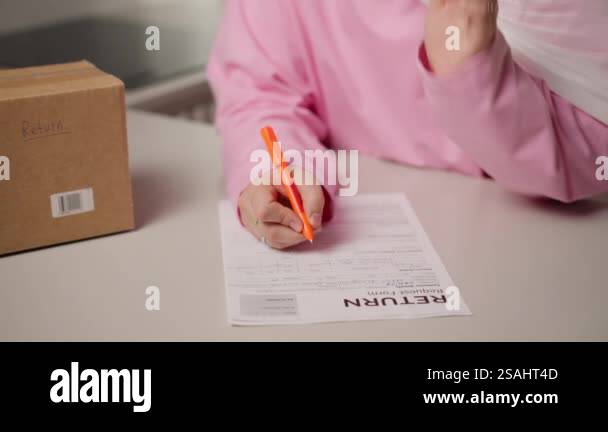 Return form is shown in close-up as Muslim woman in pink hijab fills it ...