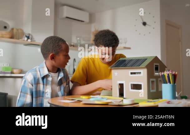 Older brother turns on light inside cardboard house model powered by ...