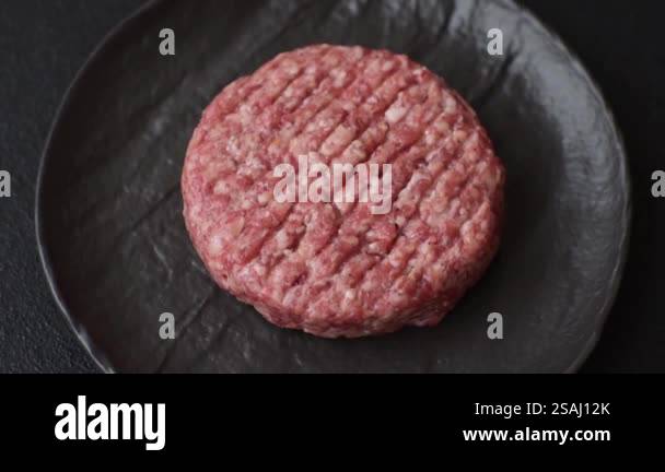Fresh raw ground beef burger patty with salt and spices on textured ...