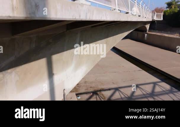 The image shows a closeup of a bridges base over a dry riverbed ...