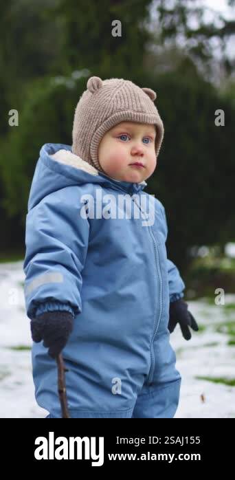 Cute one-year-old boy in warm winter overalls for a walk in a winter ...