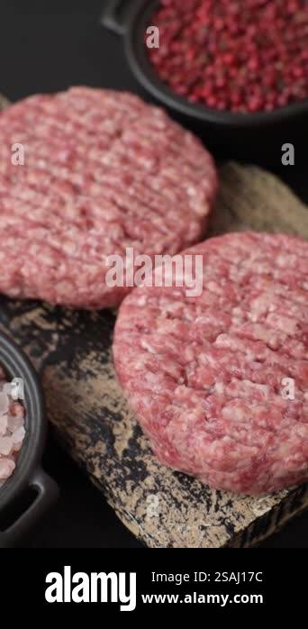 Fresh raw ground beef burger patty with salt and spices on textured ...