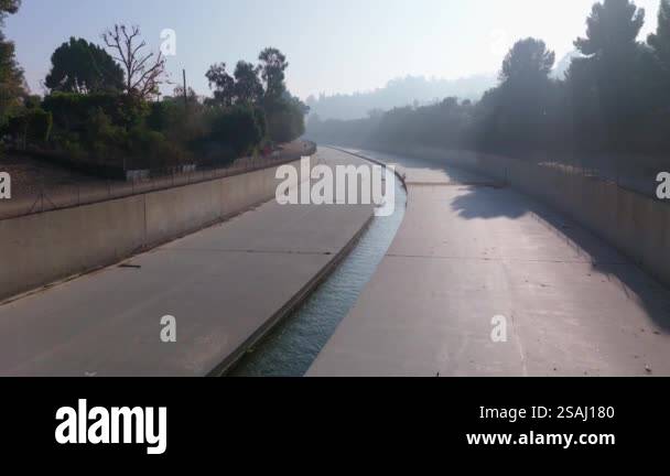 The peaceful riverbank view features lush greenery, soft golden light ...