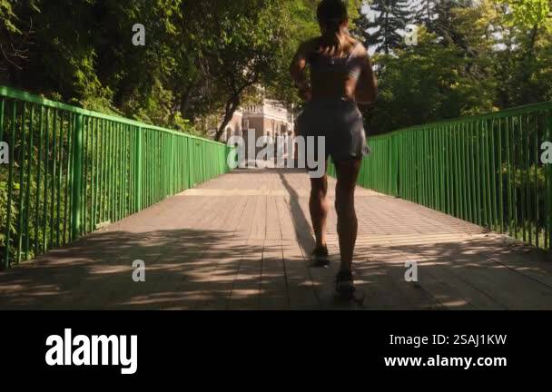 A young woman goes for a fitness run outdoors in the park. She runs ...
