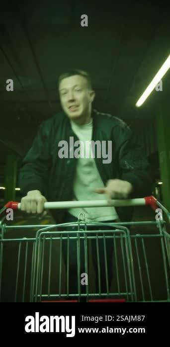 Funny young man running with shopping carts hurry up waving hand ...
