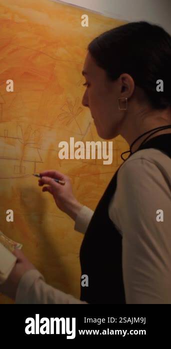 Girl approaching wall with yellow painting. Young pretty woman with ...