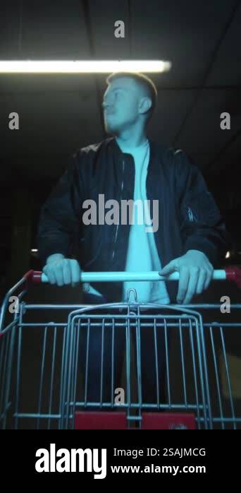 On blue light handsome man walking with shopping carts hurry up looking ...