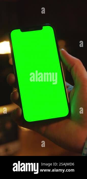 Close up mock up phone with vertical green screen. Hands using typing on a smartphone indoors ...