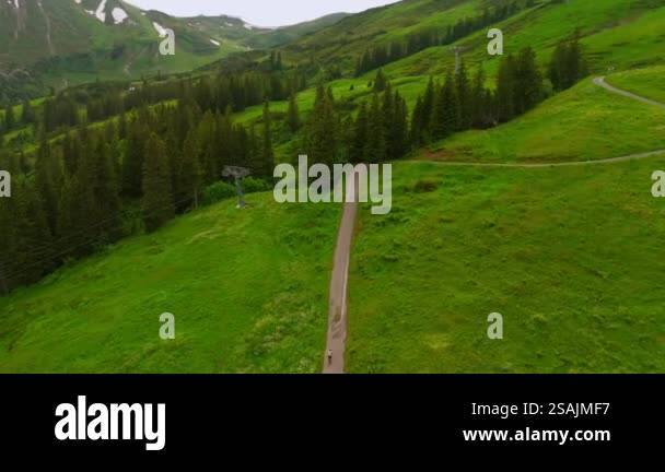Aerial view cyclist riding road bike through ski resort in Alps in ...