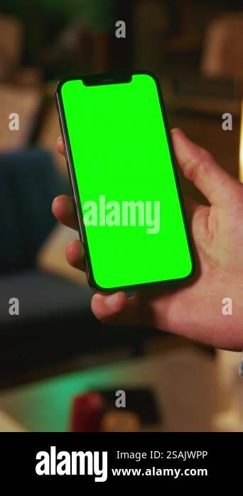 Hands using scrolling mobile phone with a vertical green screen. Social media. Smartphone. Mock ...