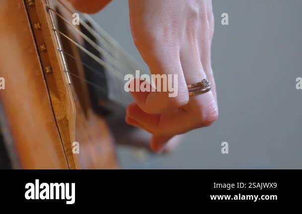 Skilled guitarist's hands moving rhythmically across acoustic guitar ...
