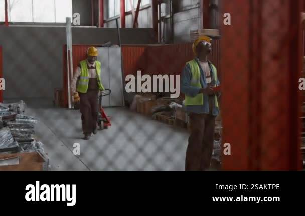 Full shot of black male factory operator in uniform, hardhat pressing ...