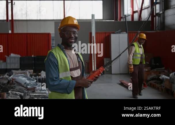 Medium full slowmo portrait of cheerful black male factory worker in ...